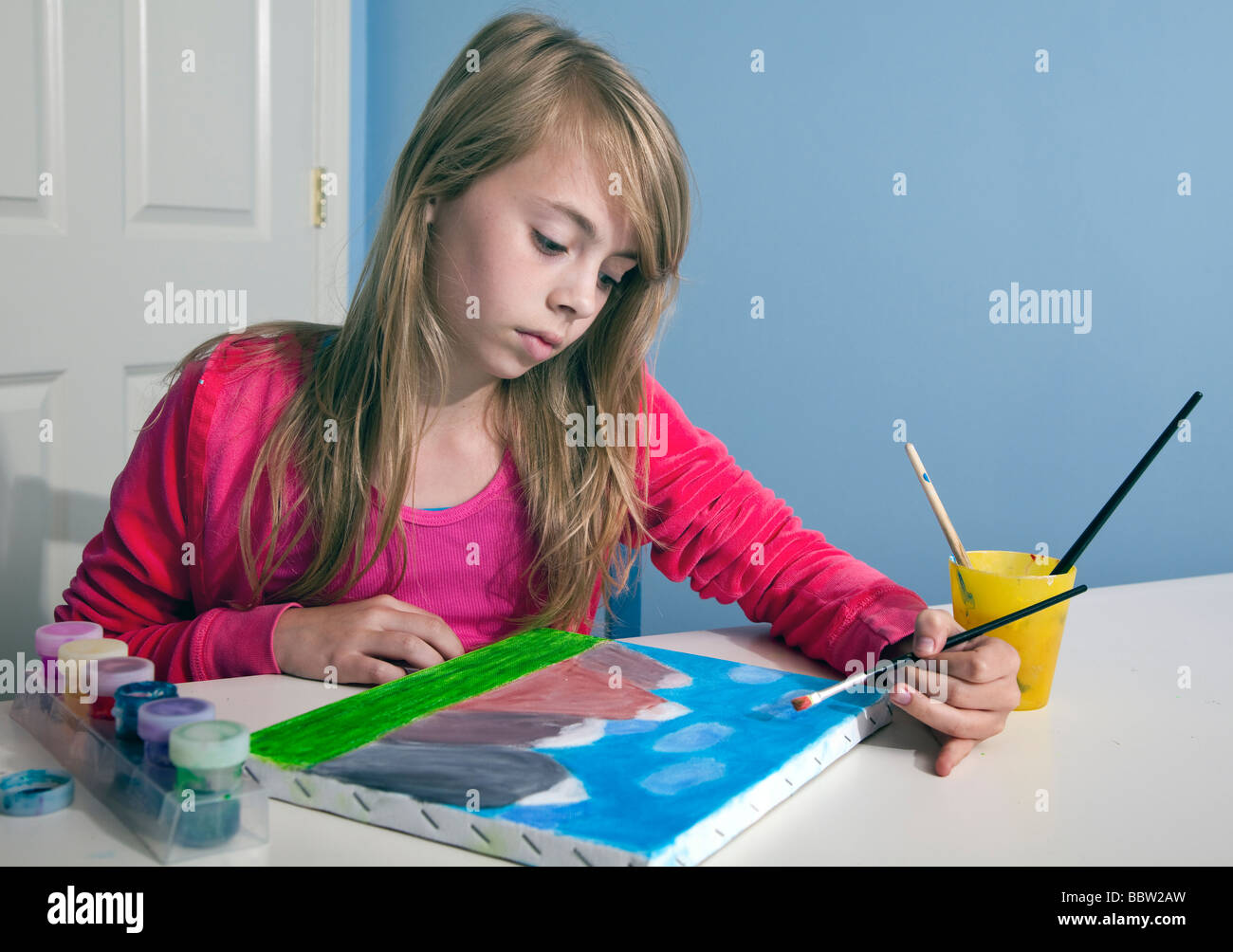 Young child using a paint brush to paint a picture Stock Photo - Alamy