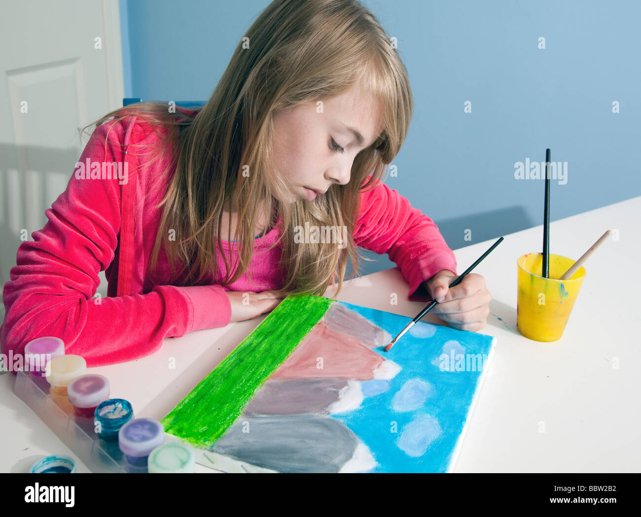 Young child using a paint brush to paint a picture Stock Photo - Alamy