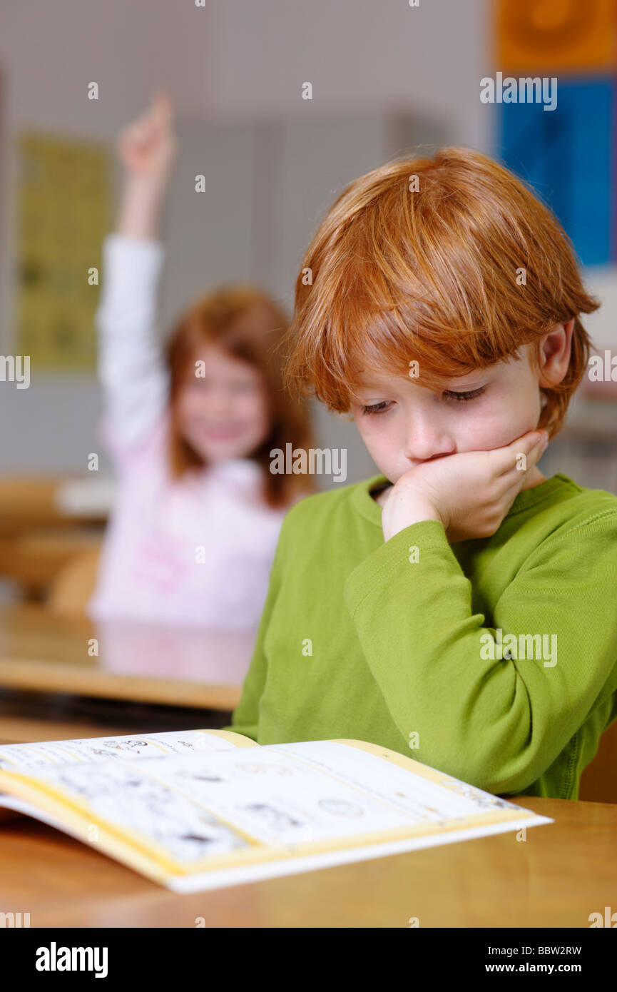 Children in a classroom in primary school, boy daydreaming or looking ...