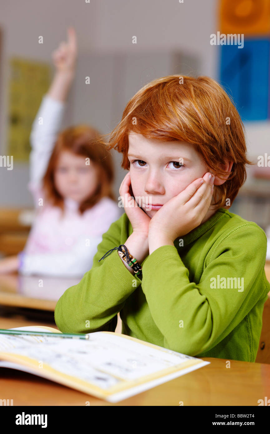 Children in a classroom in primary school, boy daydreaming or looking ...