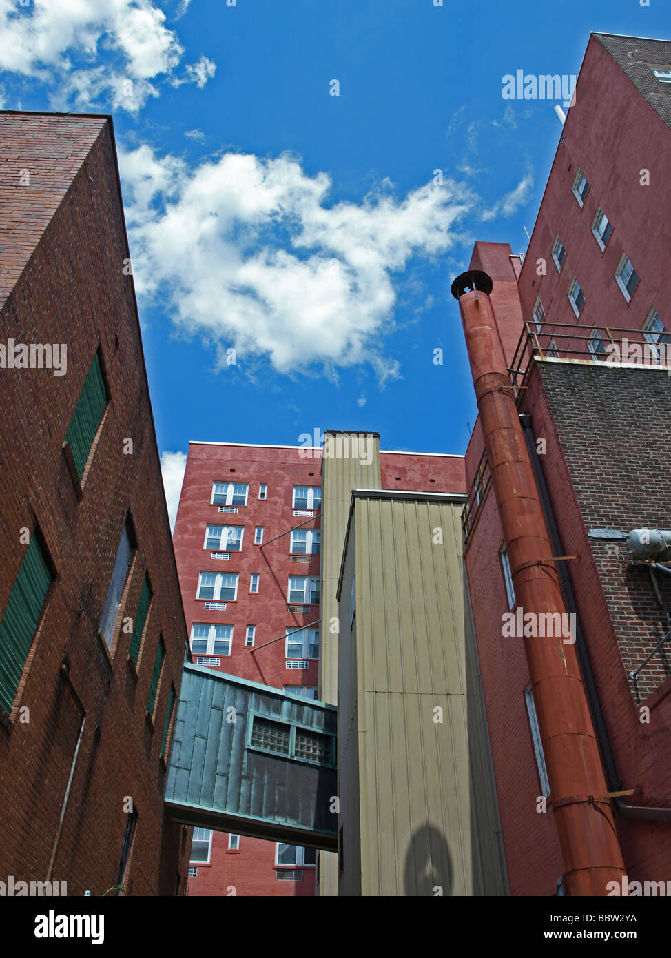 alley way in commercial zone showing buildings reaching to cloudy sky ...