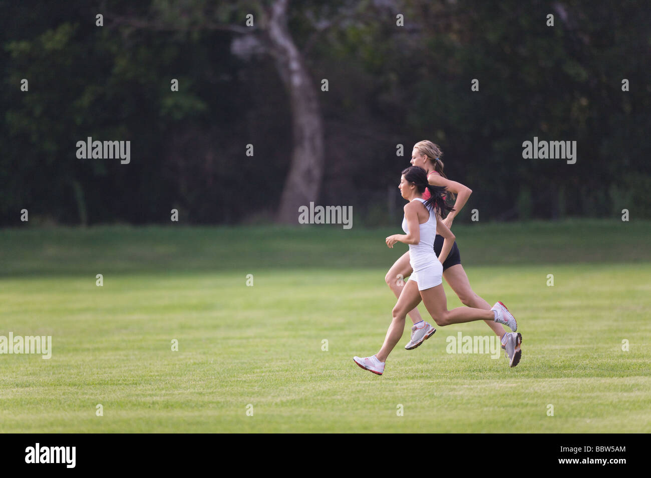 Two Women Running Together on Grass Stock Photo - Alamy
