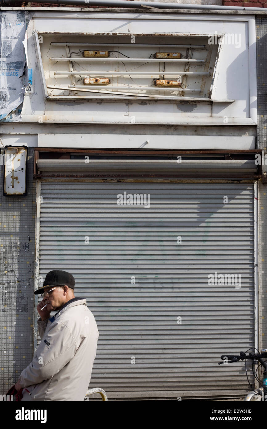 A local man stops for a quiet smoke on a cigarette near a closed shop ...