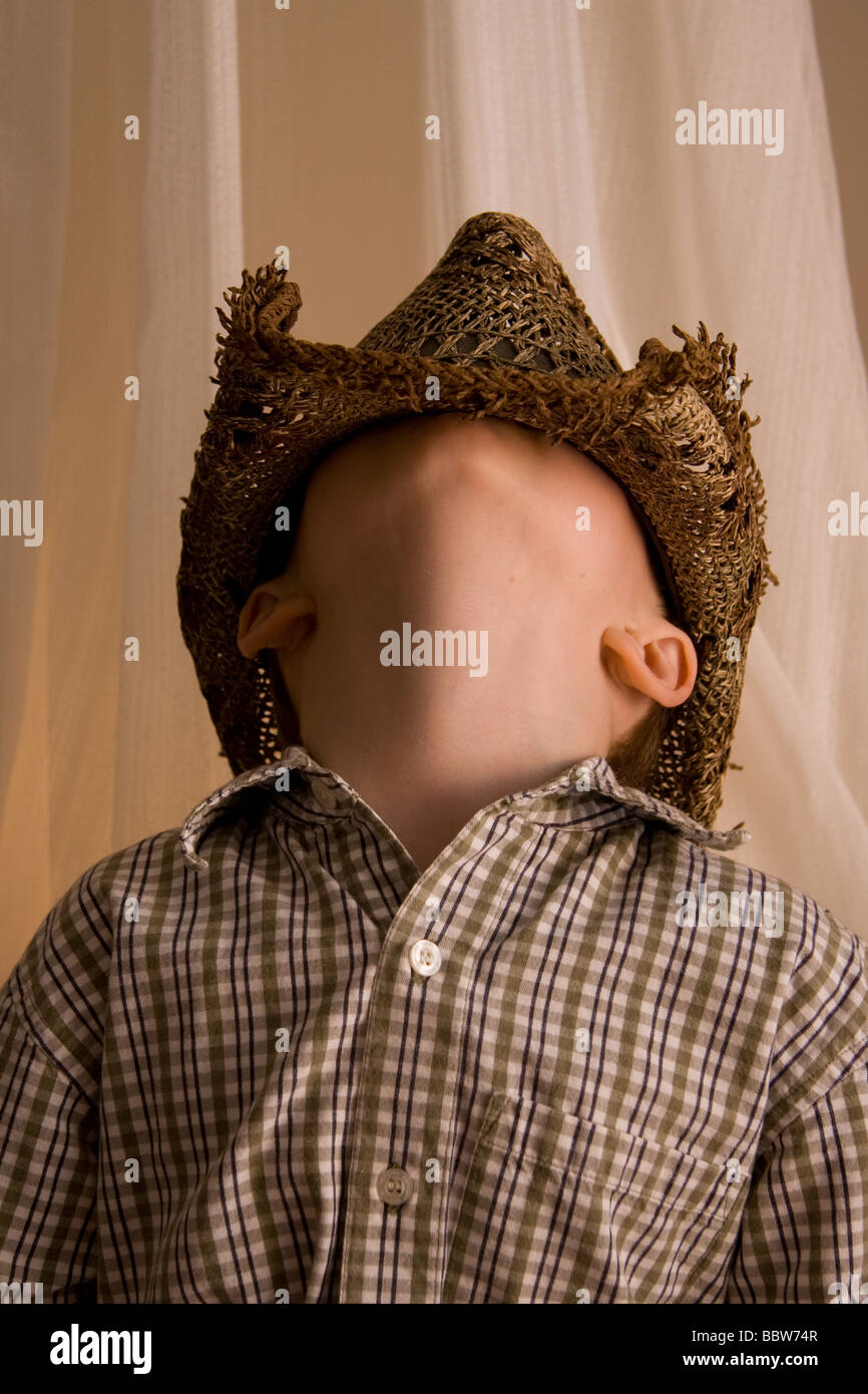 Boy playing with cowboy hat on face Stock Photo - Alamy