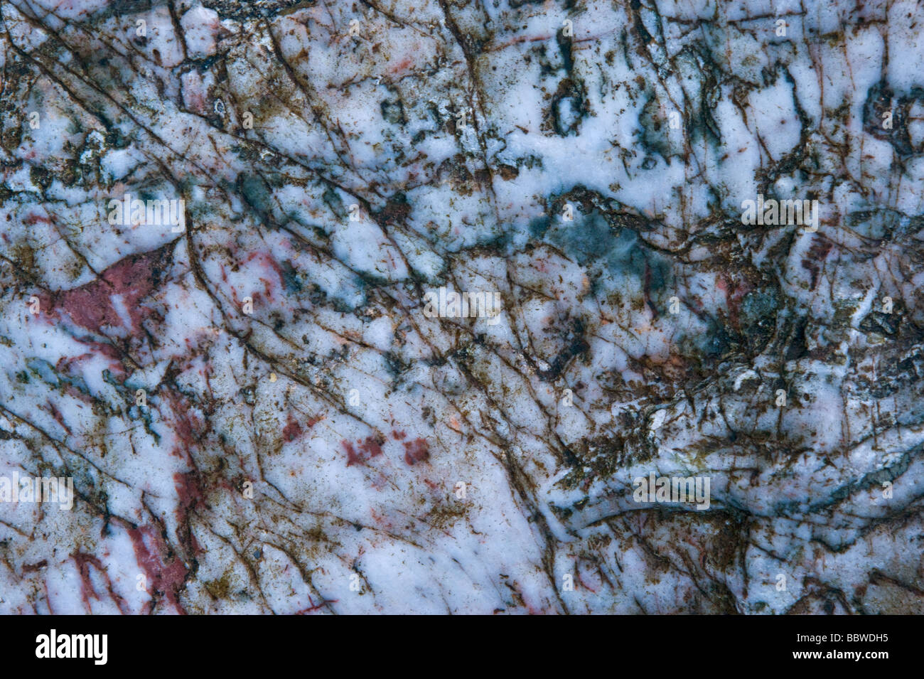 A close up of a cut away of granite quartz rock with red, blue and ...