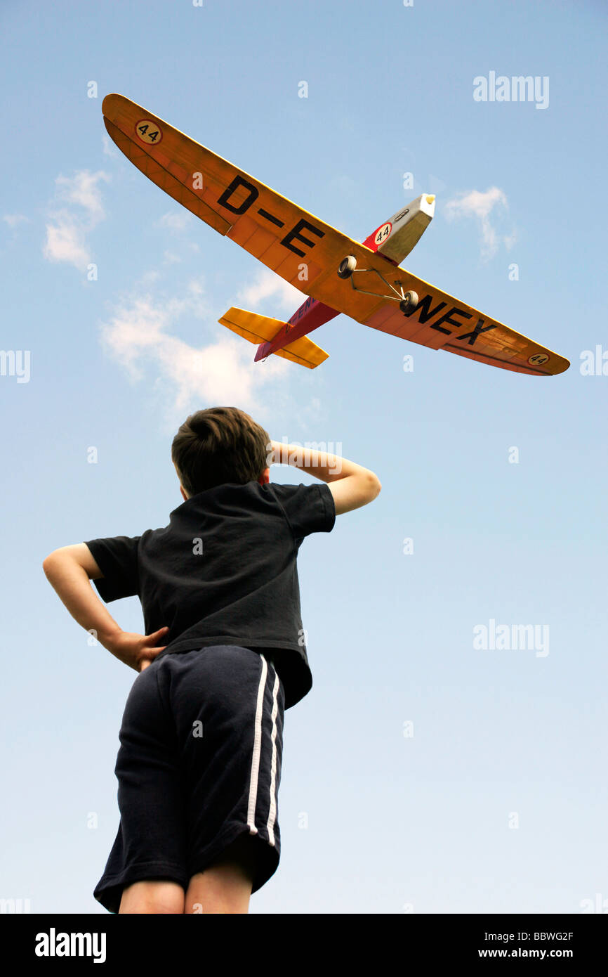 A young boy watching a model plane fly overhead Stock Photo - Alamy