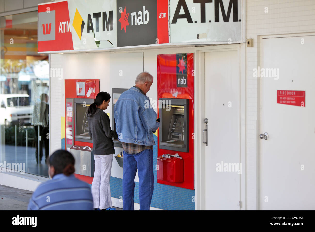 Man and a woman using ATM cash teller machines Stock Photo - Alamy
