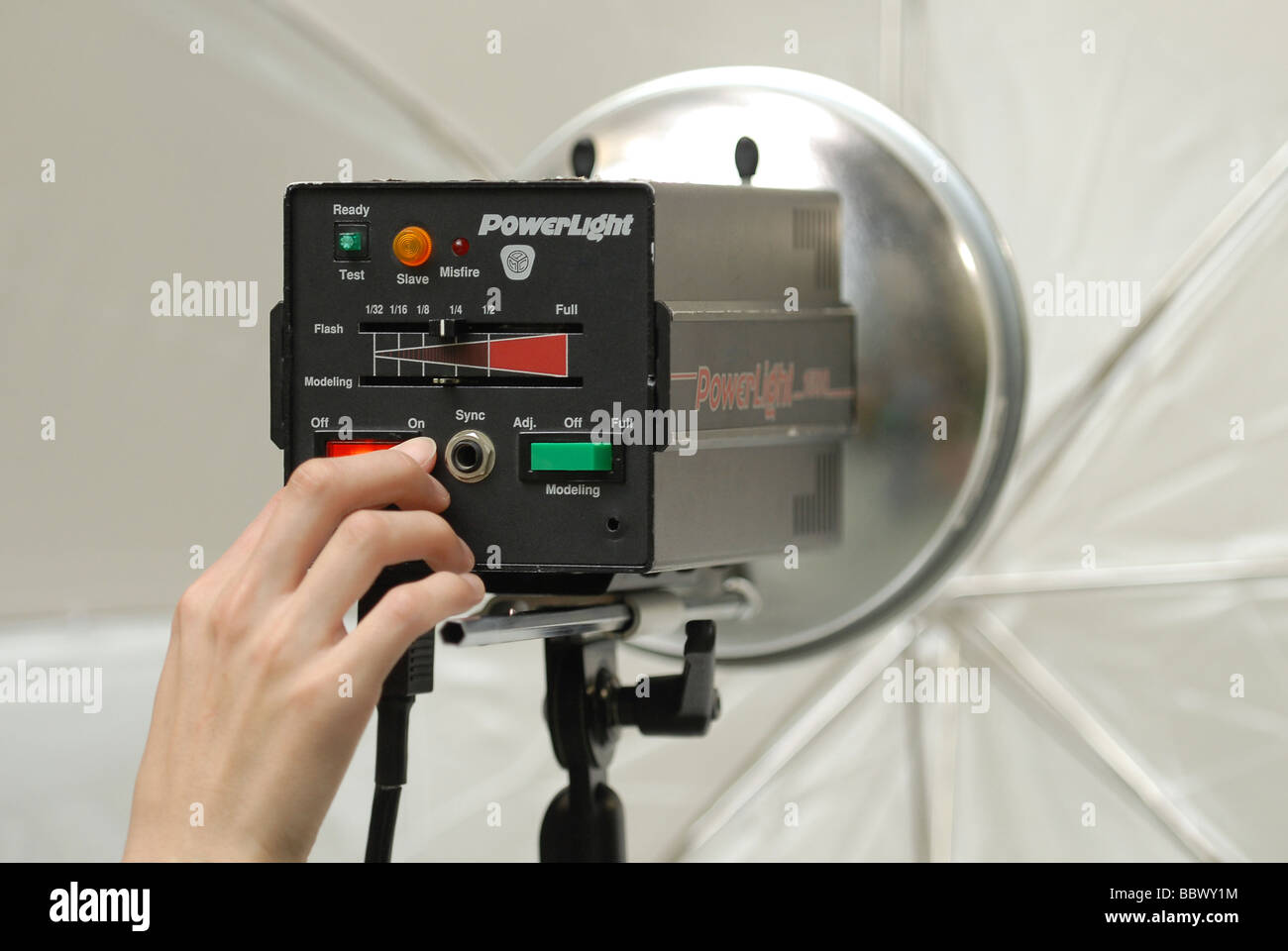 Turning on a professional photo studio light with umbrella attached ...