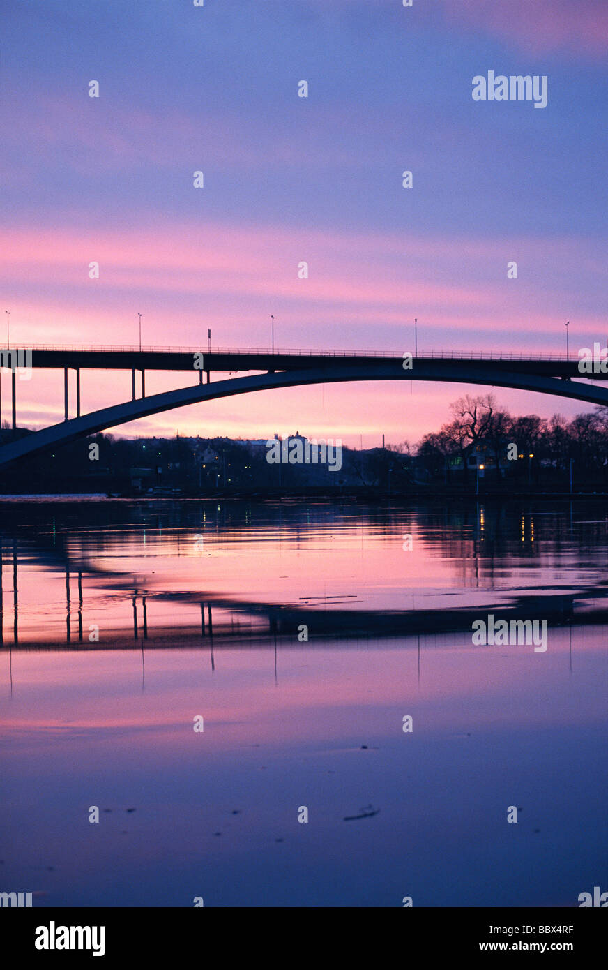 A bridge over calm water in the sunset Stock Photo - Alamy