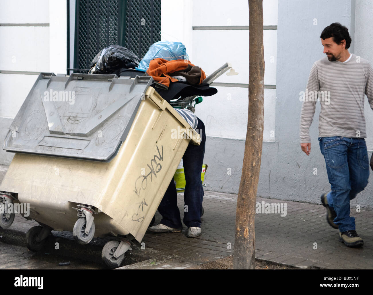 man dives into garbage container in search for food in street in ...