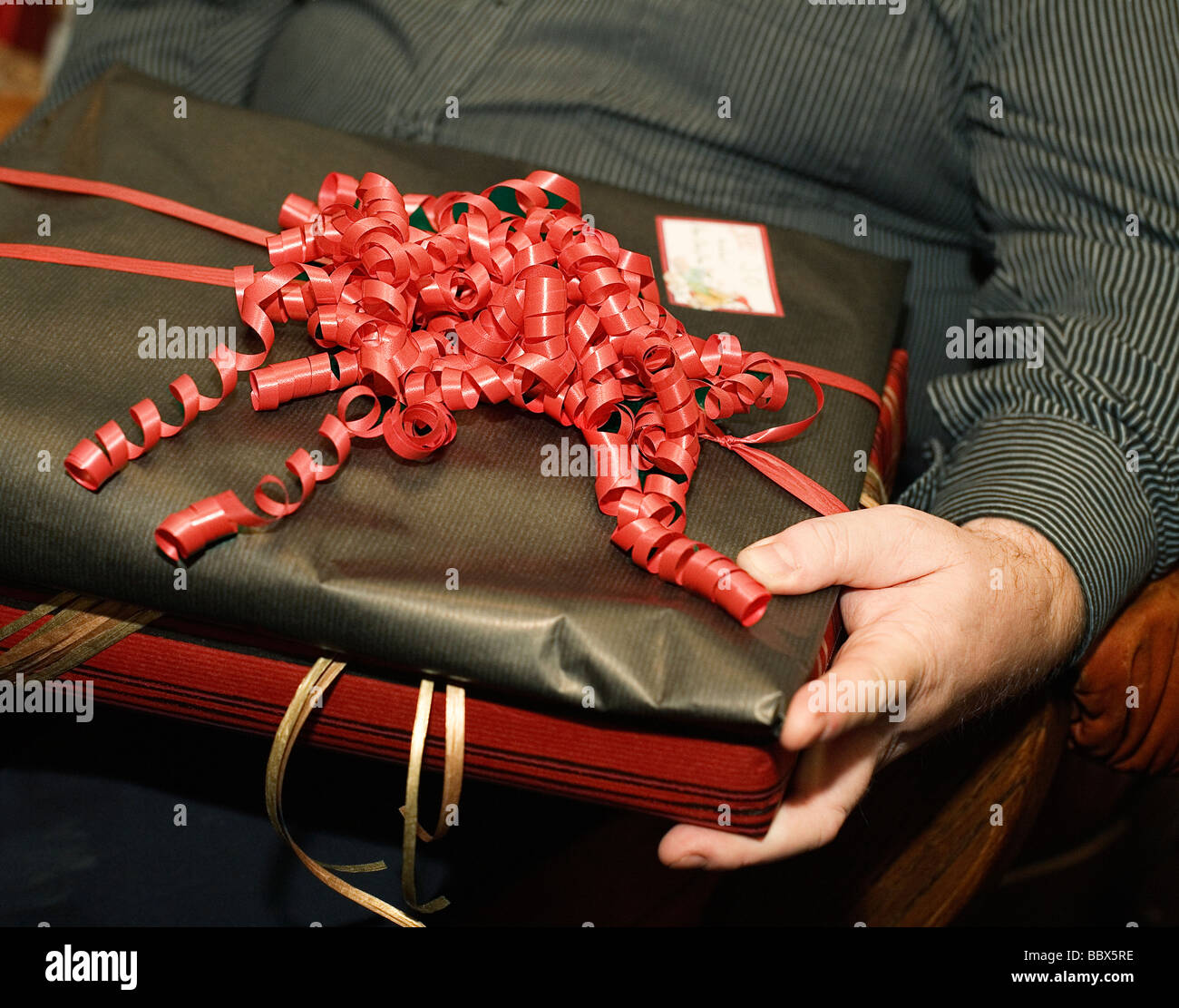 A man holding Christmas presents wrapped with red strings Sweden Stock ...