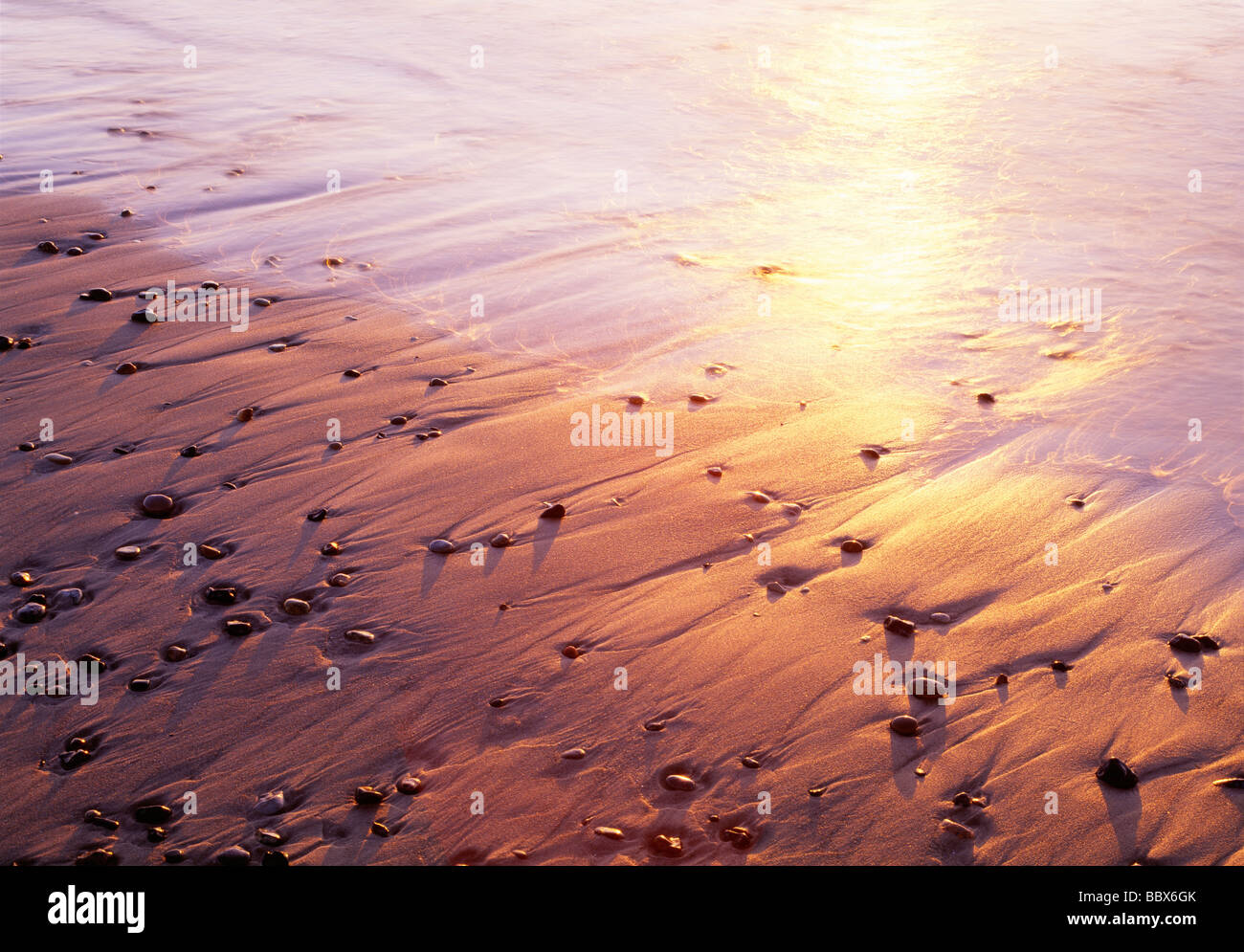 Pebbles on sand at water s edge Stock Photo - Alamy