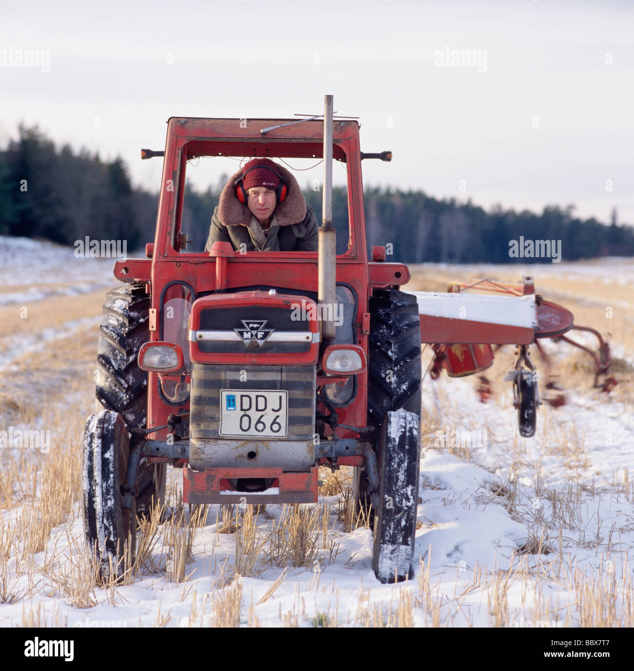 Young man driving tractor in snow-covered field Stock Photo - Alamy