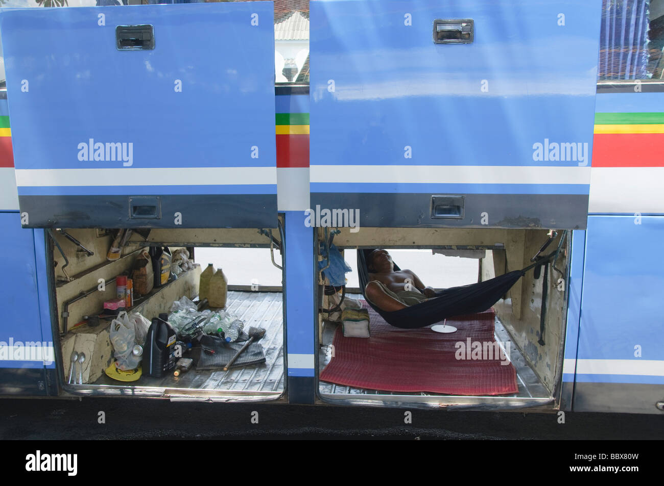 bus driver sleeping in a hammock under his bus in Bangkok Thailand ...
