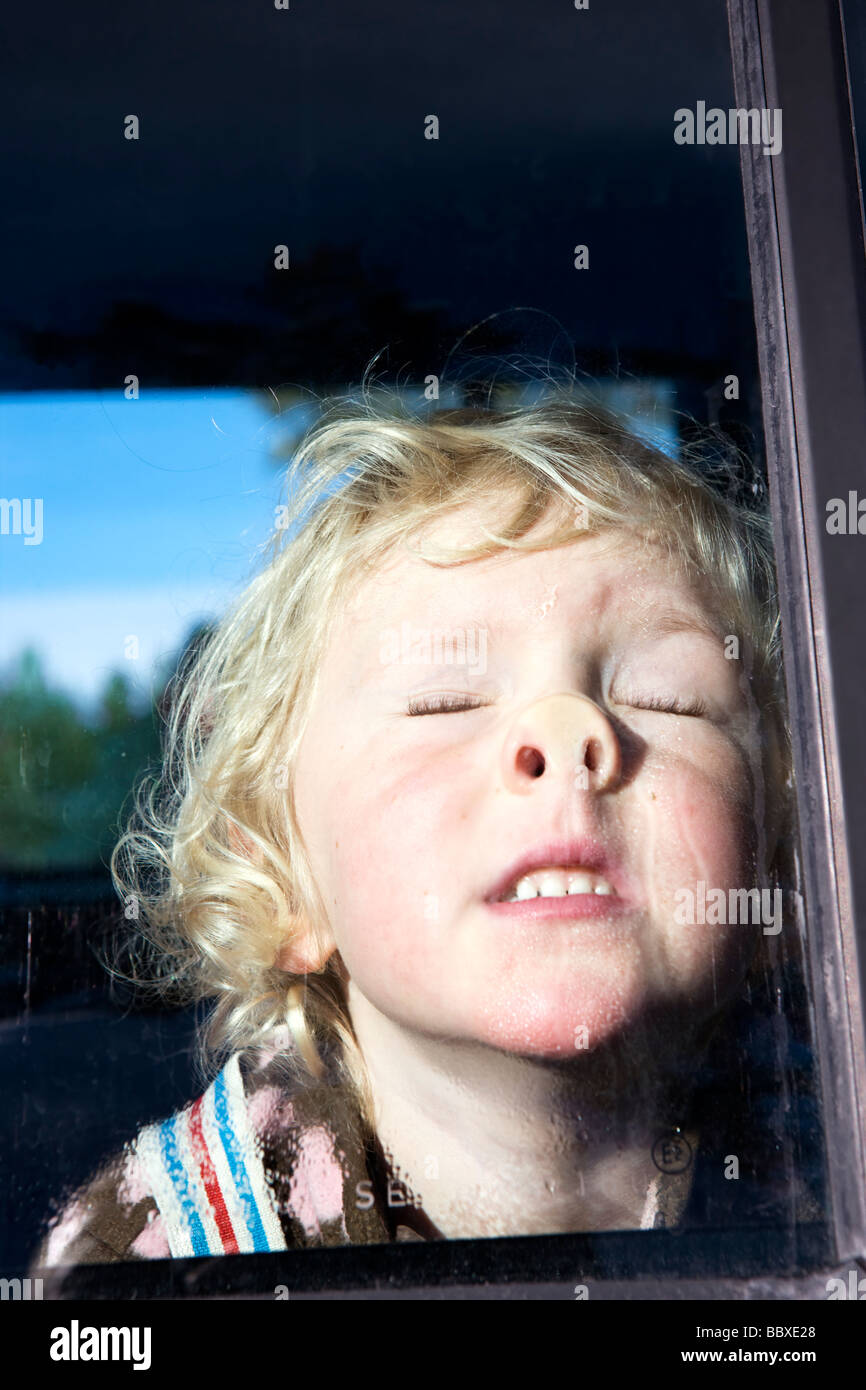 A blond girl pushing her face against a window Stock Photo - Alamy