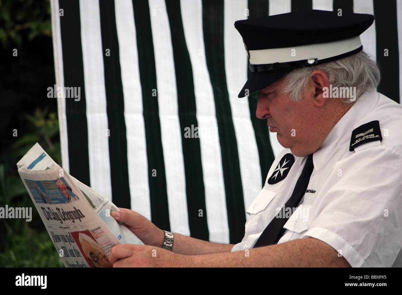 A red cross worker in uniform reading the local daily telegraph ...
