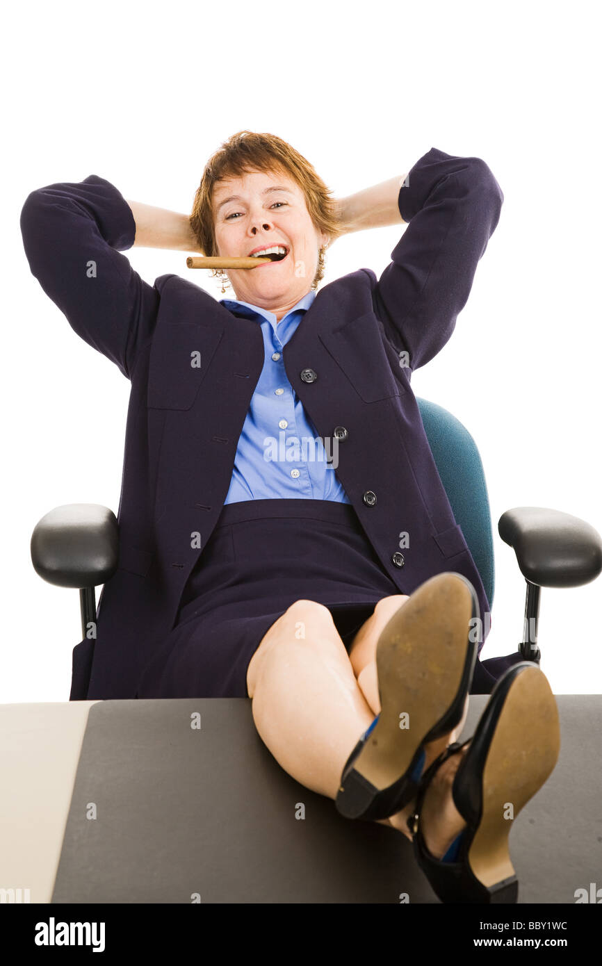 Mature businesswoman smoking a cigar with her feet on her desk Isolated ...