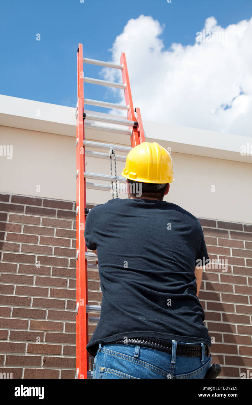 Construction worker using a ladder to climb to the top of a building ...