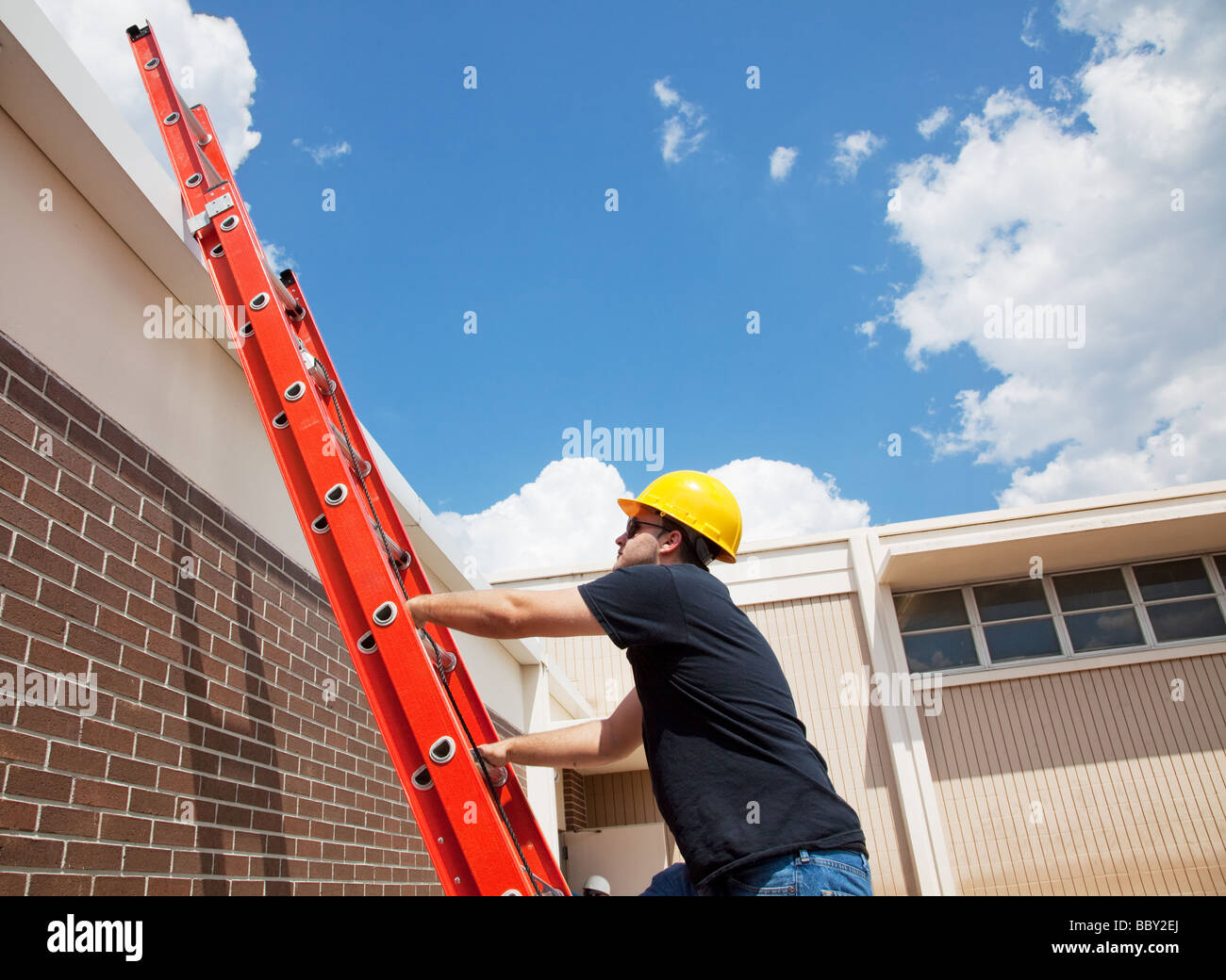 Construction worker climbing up to the roof of a building Wide view ...