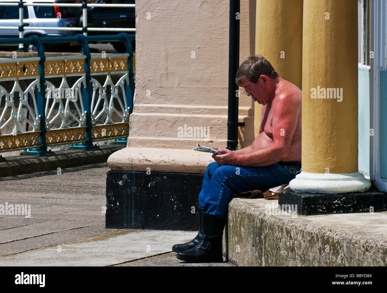 A sunburnt man sitting on the pier at Penarth in South Wales. Photo by ...