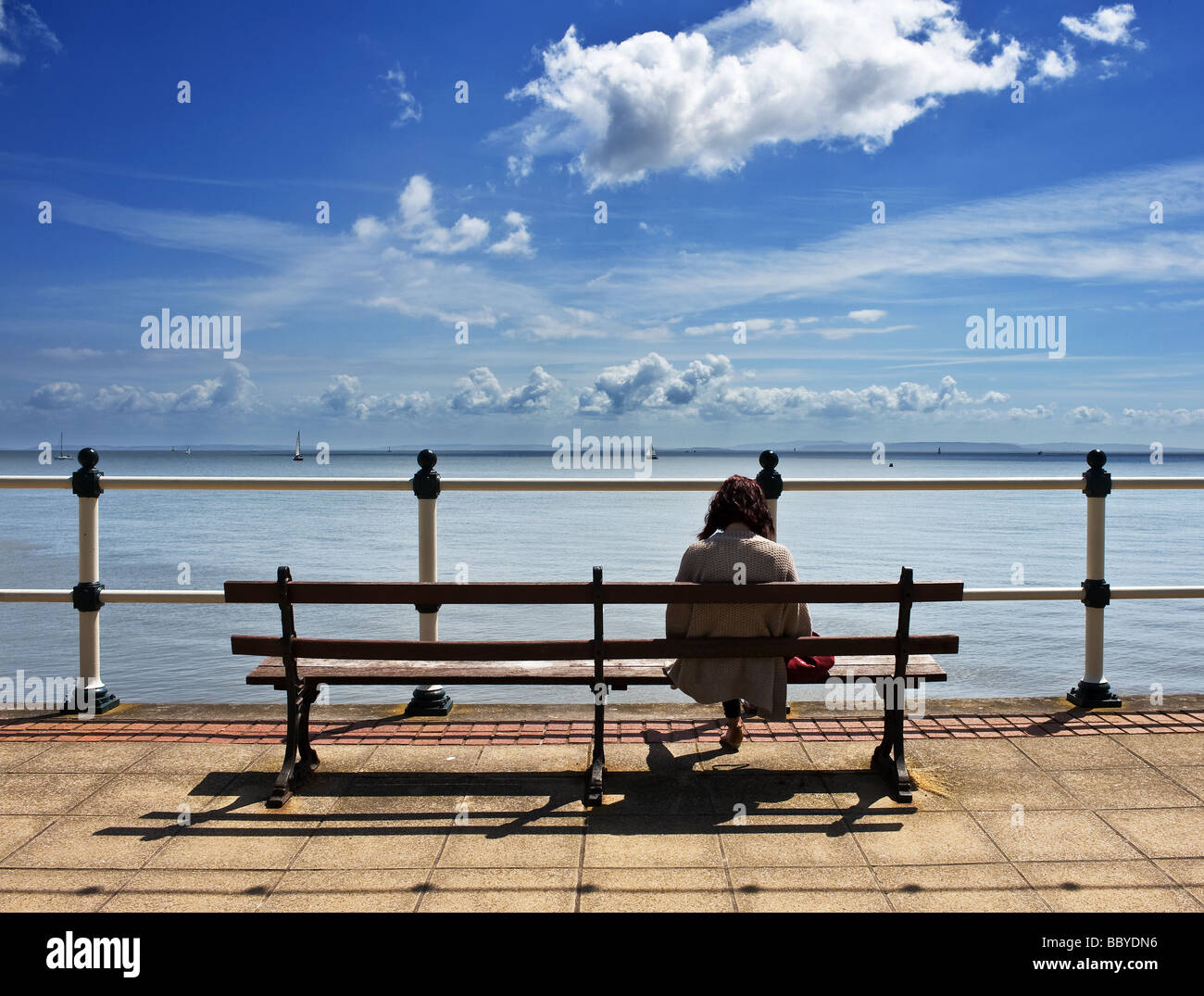 A female sitting on her own on a bench on the Esplanade at Penarth in ...