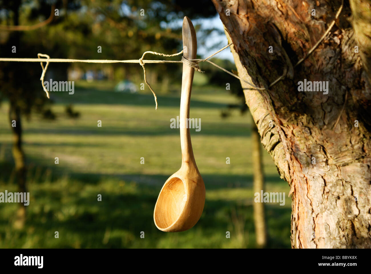 Old wooden hand carved ladle hanging by twine from a tree drying in ...