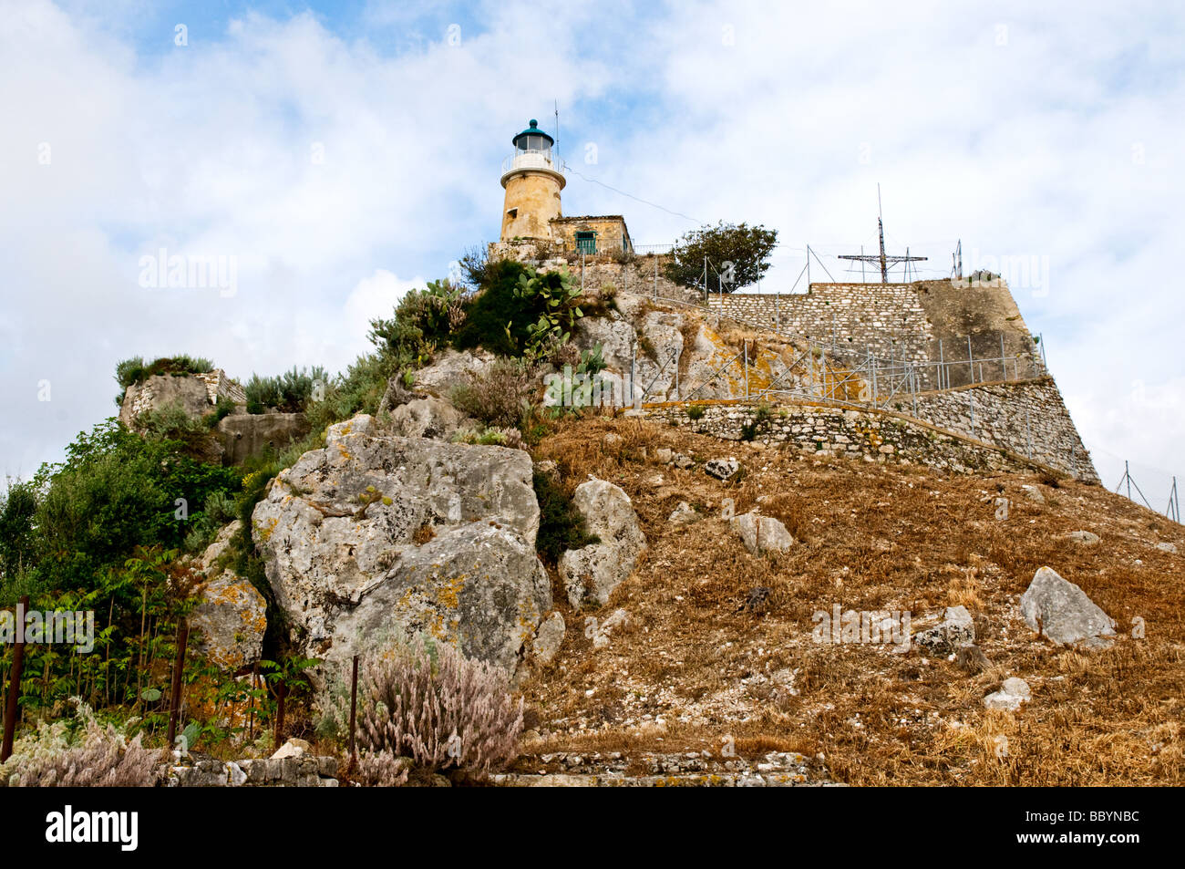 A lighthouse and cross protected by a steep rocky slope stand on the ...