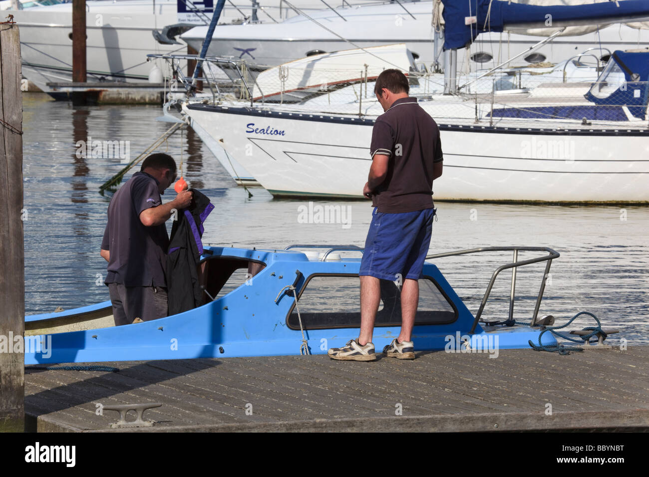 Two Men on board on a small motor boat moor on the Pontoon at the Jolly ...