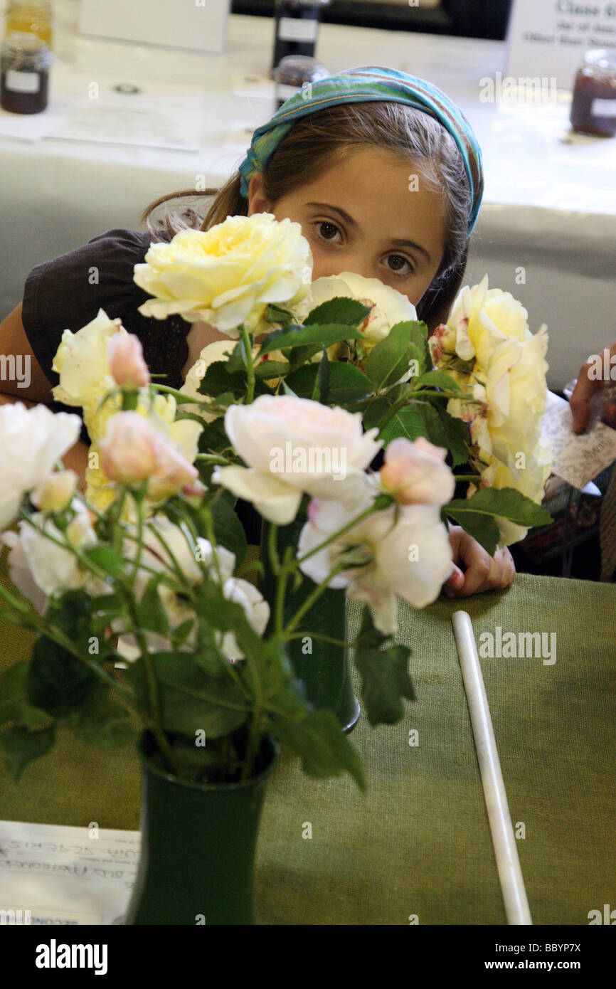 Young girl sniffing roses at a horticulture show. The flowers have been ...