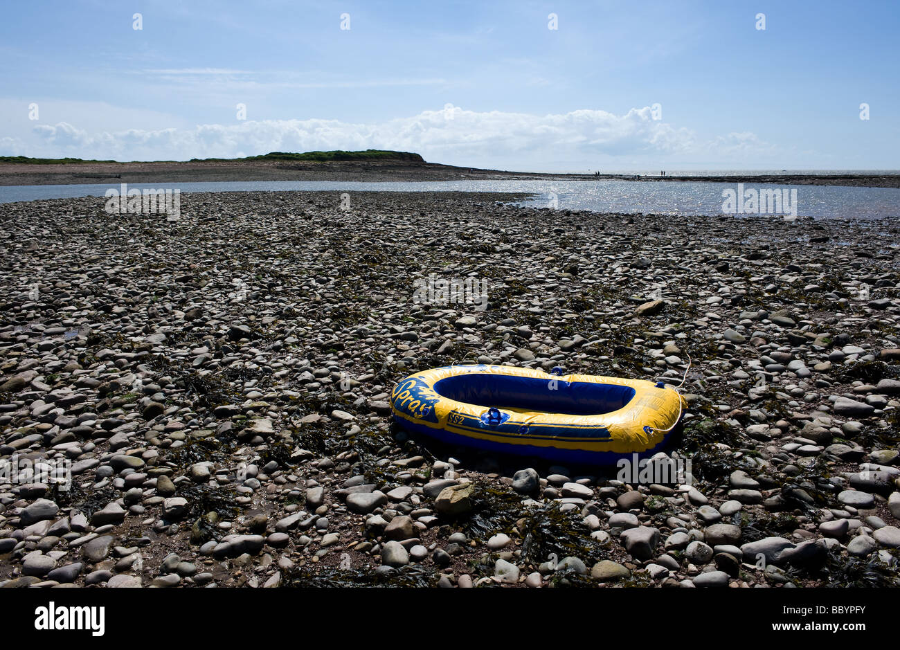A punctured inflatable dinghy left on the pebble beach at Sully in ...