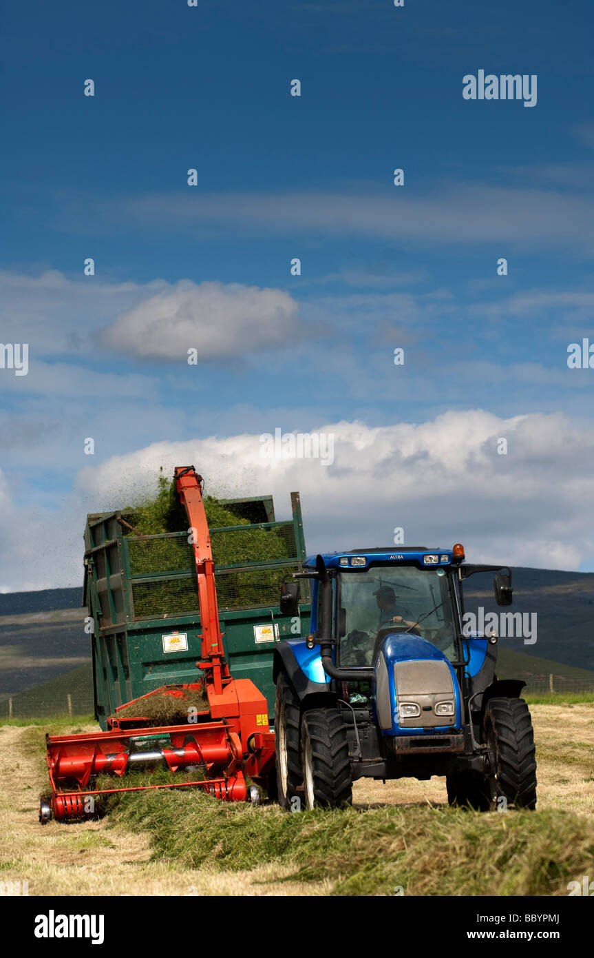 Valtra tractor pulling a Kverneland forage harvester and trailer making ...