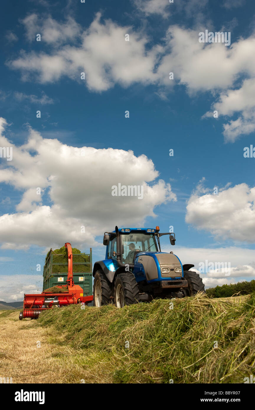 Valtra tractor pulling a Kverneland forage harvester and trailer making ...
