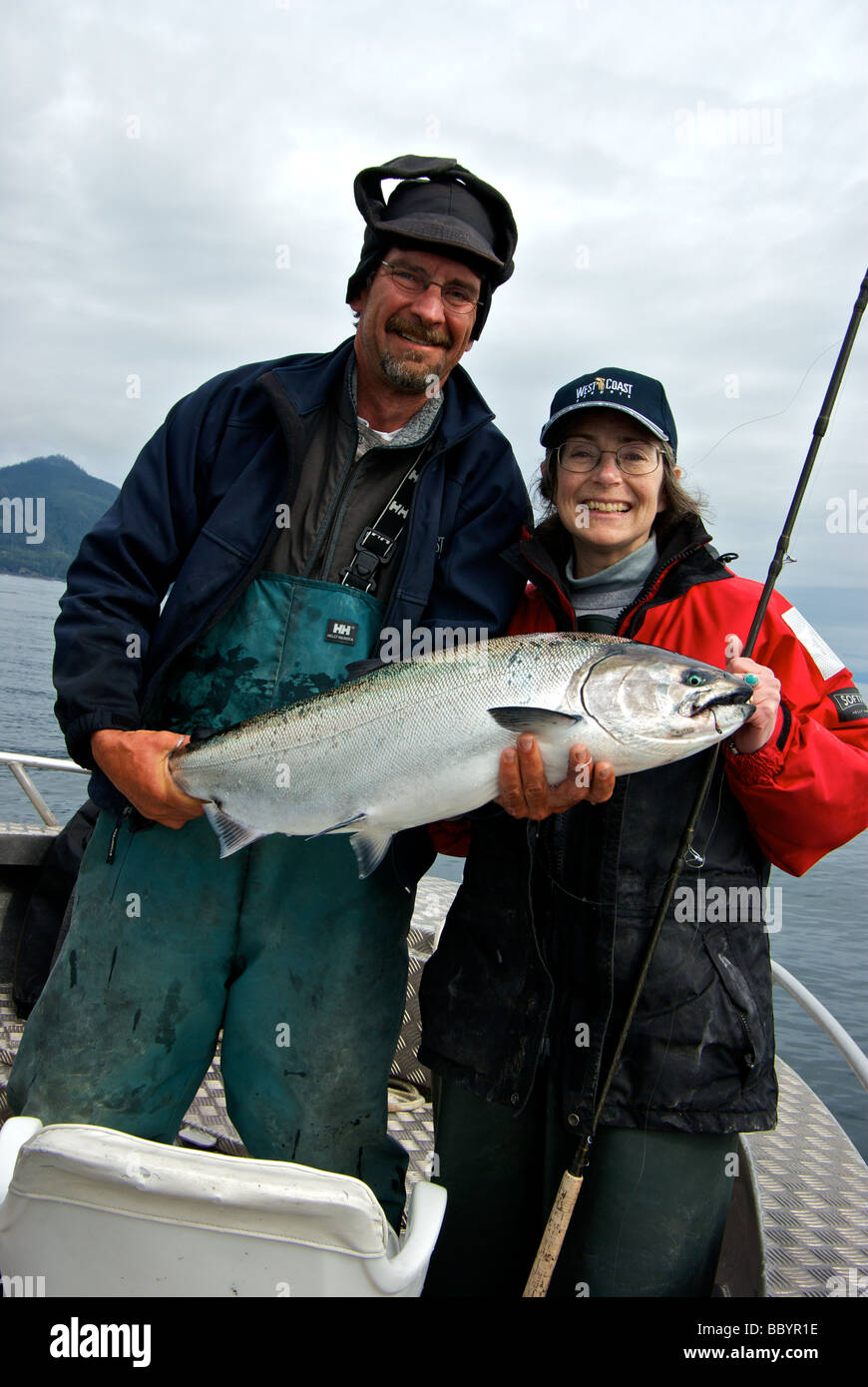 Female angler wearing resort baseball cap with fishing guide holding a ...