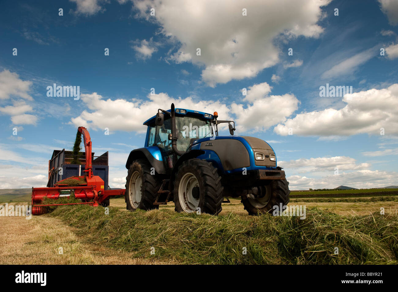 Valtra tractor pulling a Kverneland forage harvester and trailer making ...