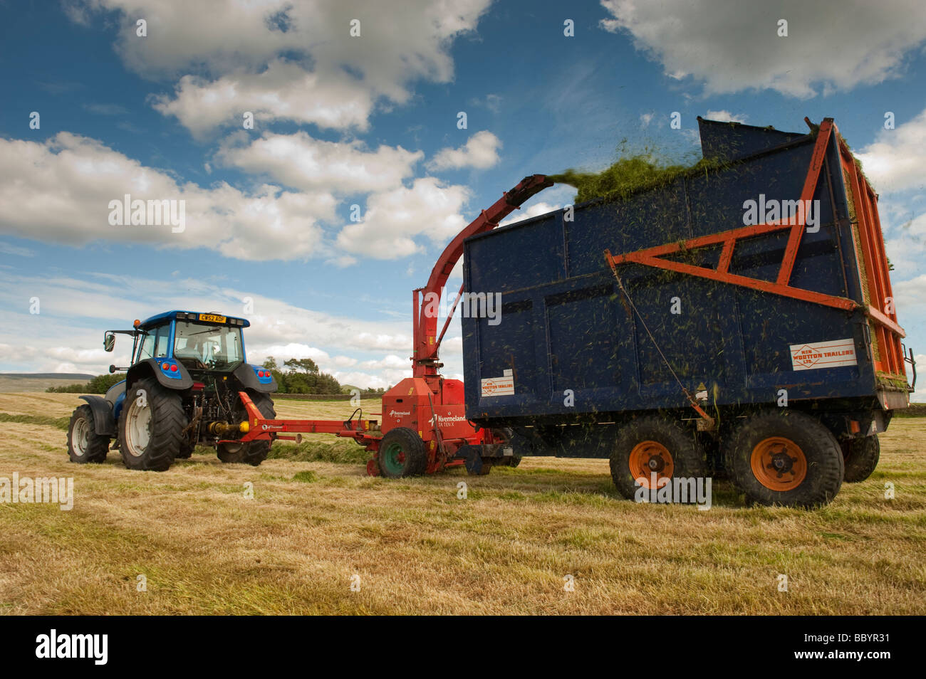 Valtra tractor pulling a Kverneland forage harvester and trailer making ...