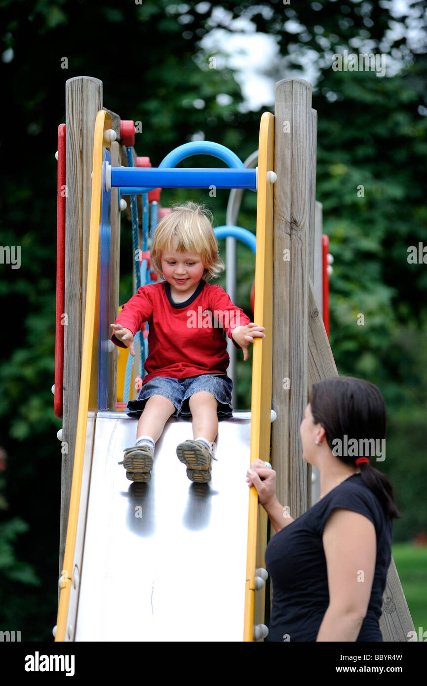 Child blonde boy sliding down the slide on the playground Stock Photo ...