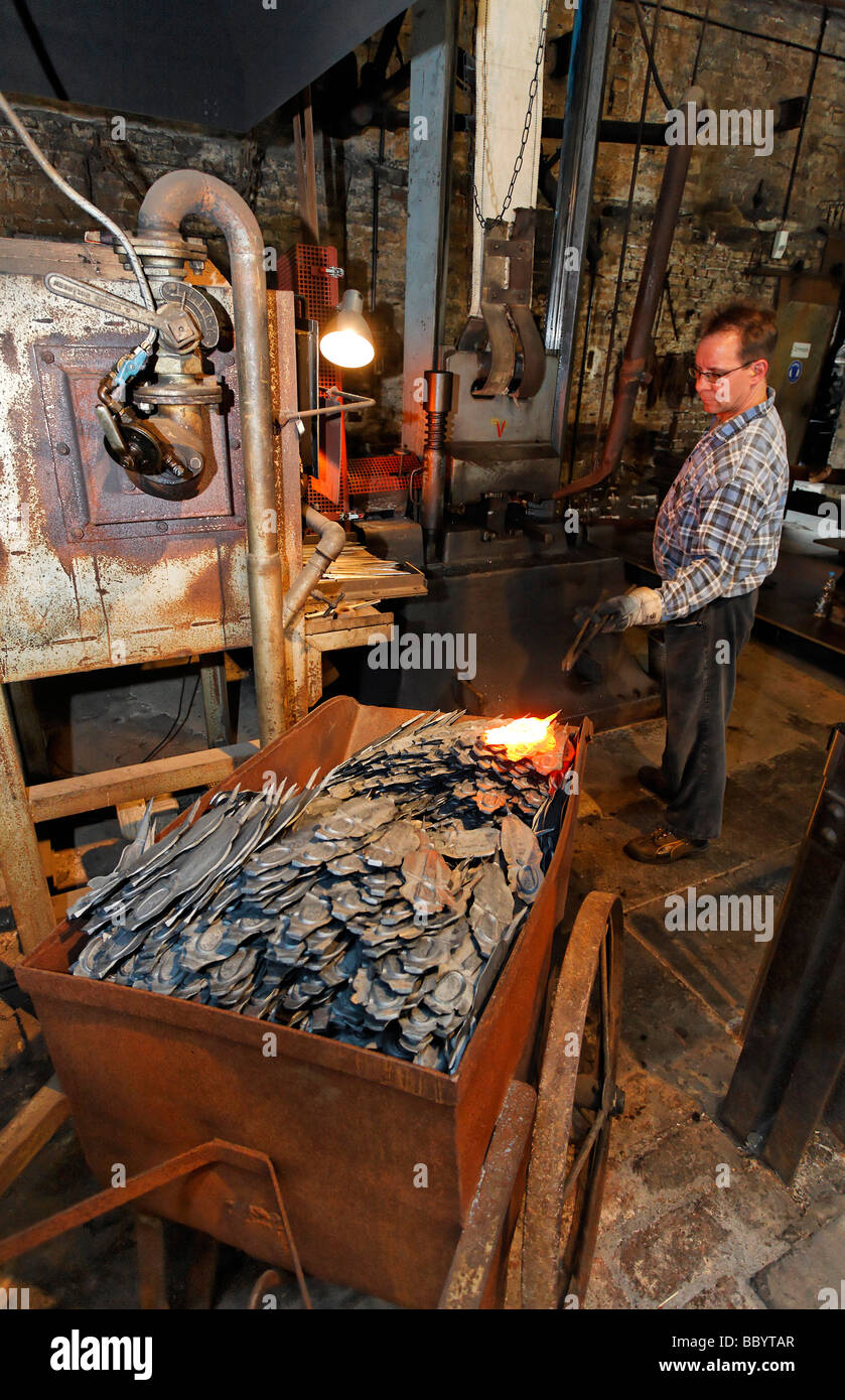 Worker putting a smoldering scissor blank into an iron cart, scissor ...