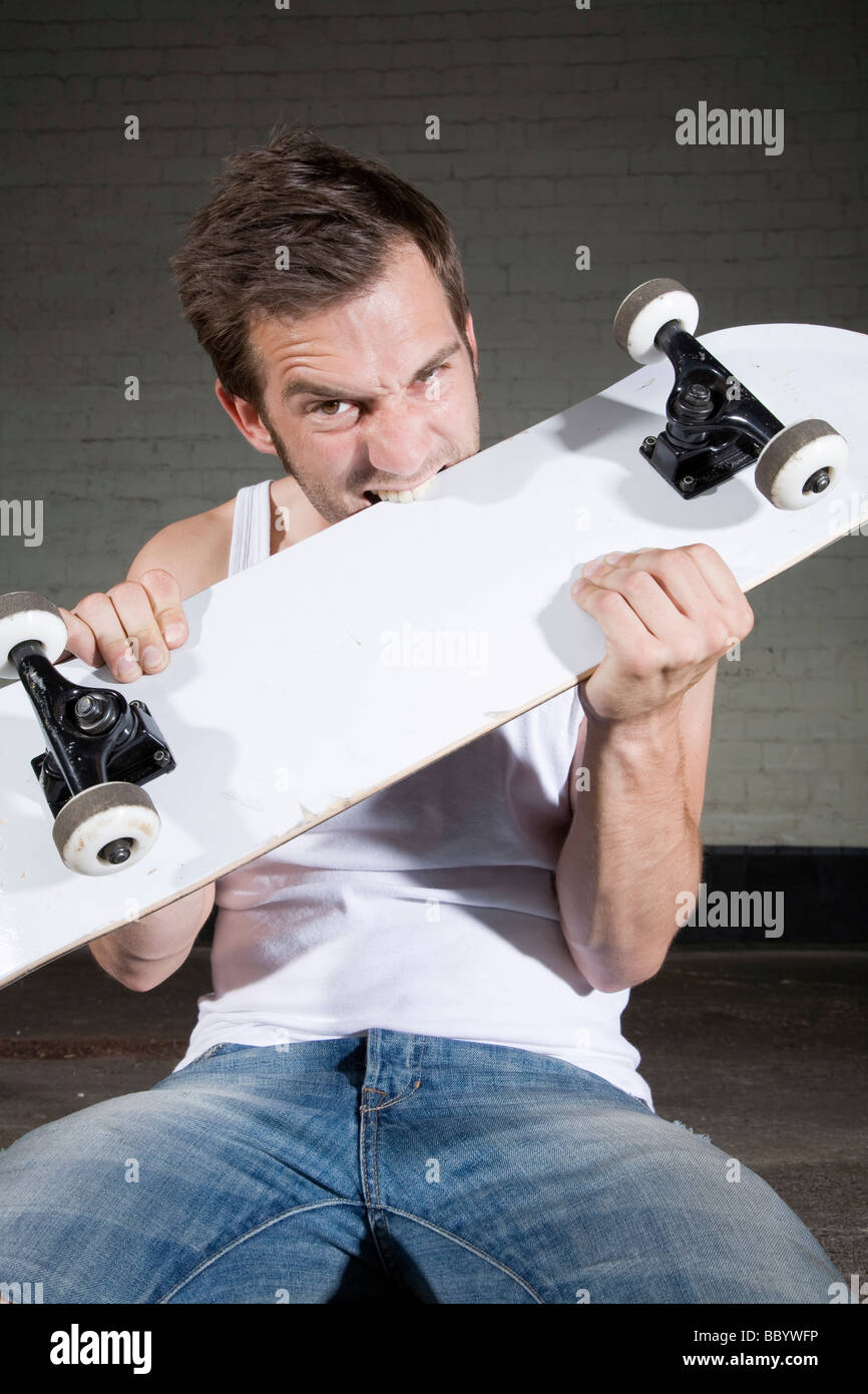 Skateboarder biting into his board Stock Photo - Alamy