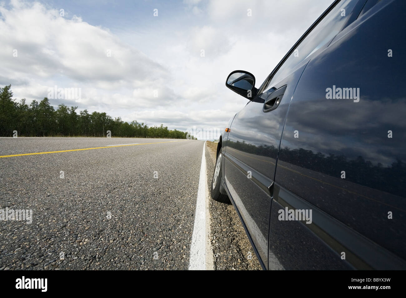 small blue car standing on the road side wide angle perspective view ...