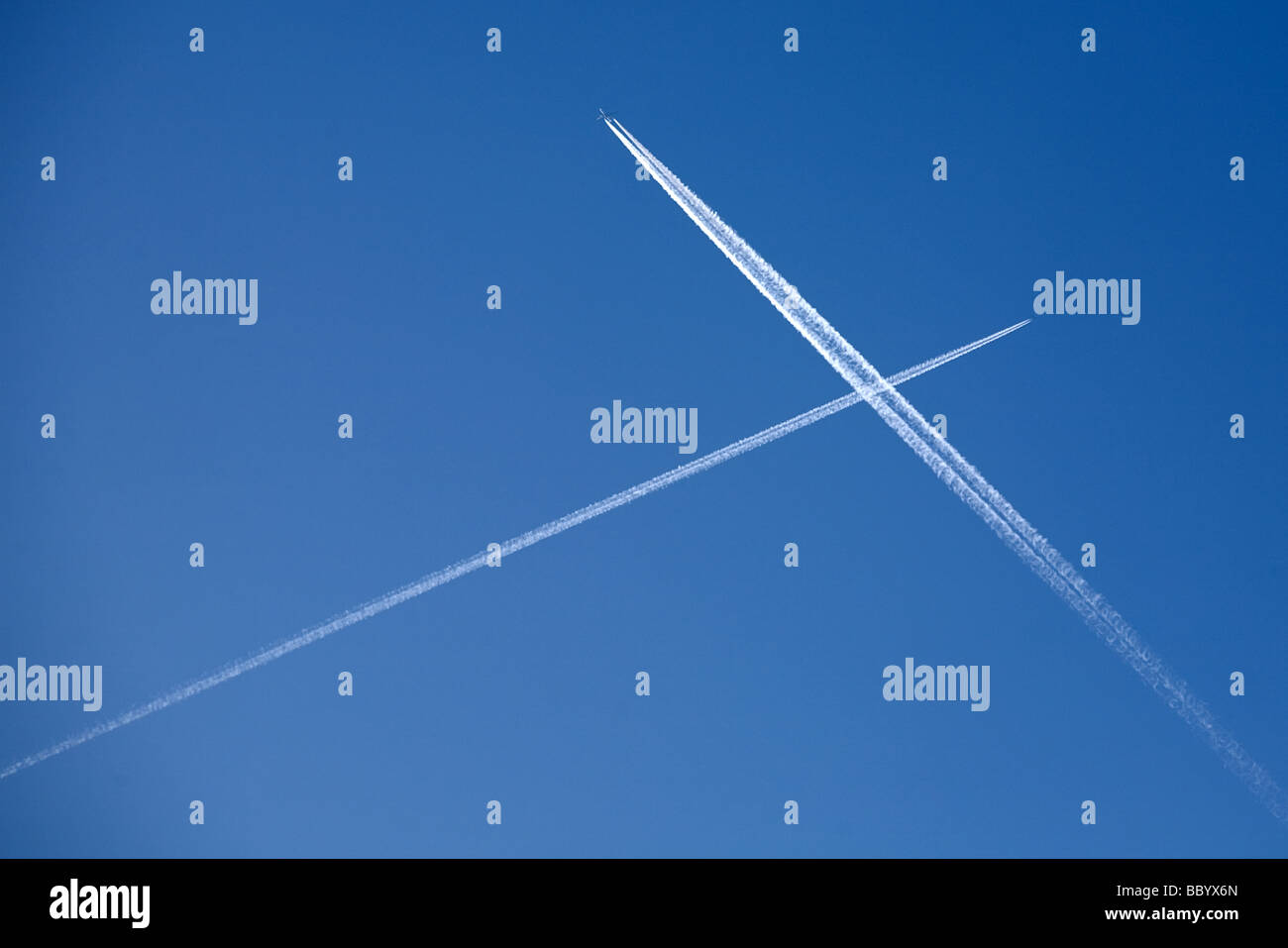 Two crossing traces from planes in clean blue sky Stock Photo - Alamy
