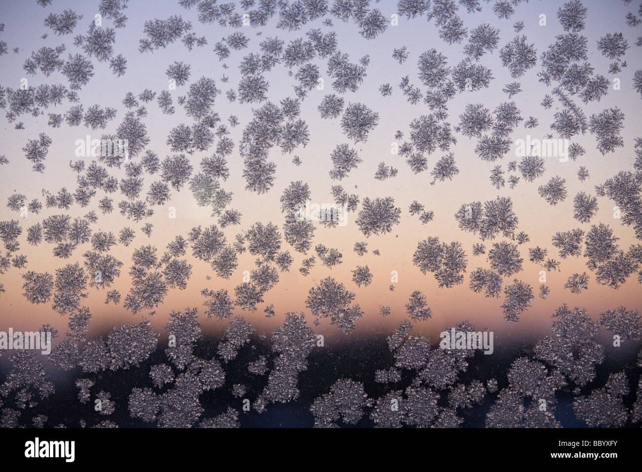 winter pattern of snowflakes on frosty window with sunset background ...