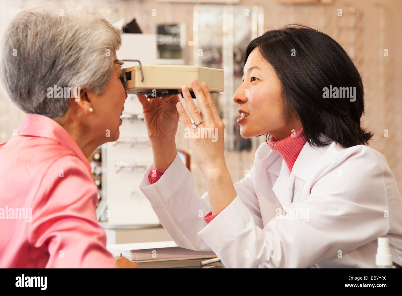 Korean optician giving woman eye exam Stock Photo - Alamy