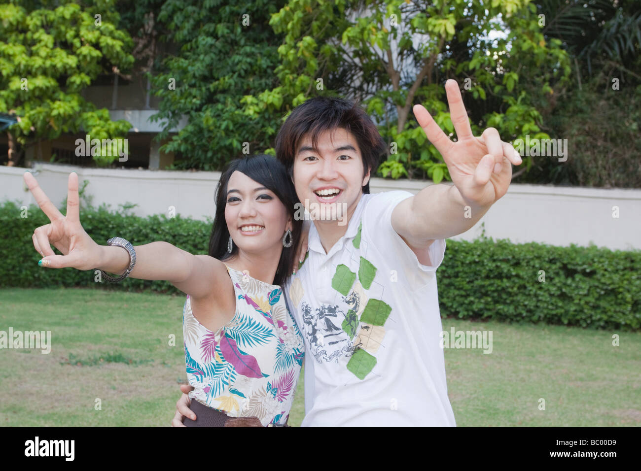 Asian couple making peace sign Stock Photo - Alamy