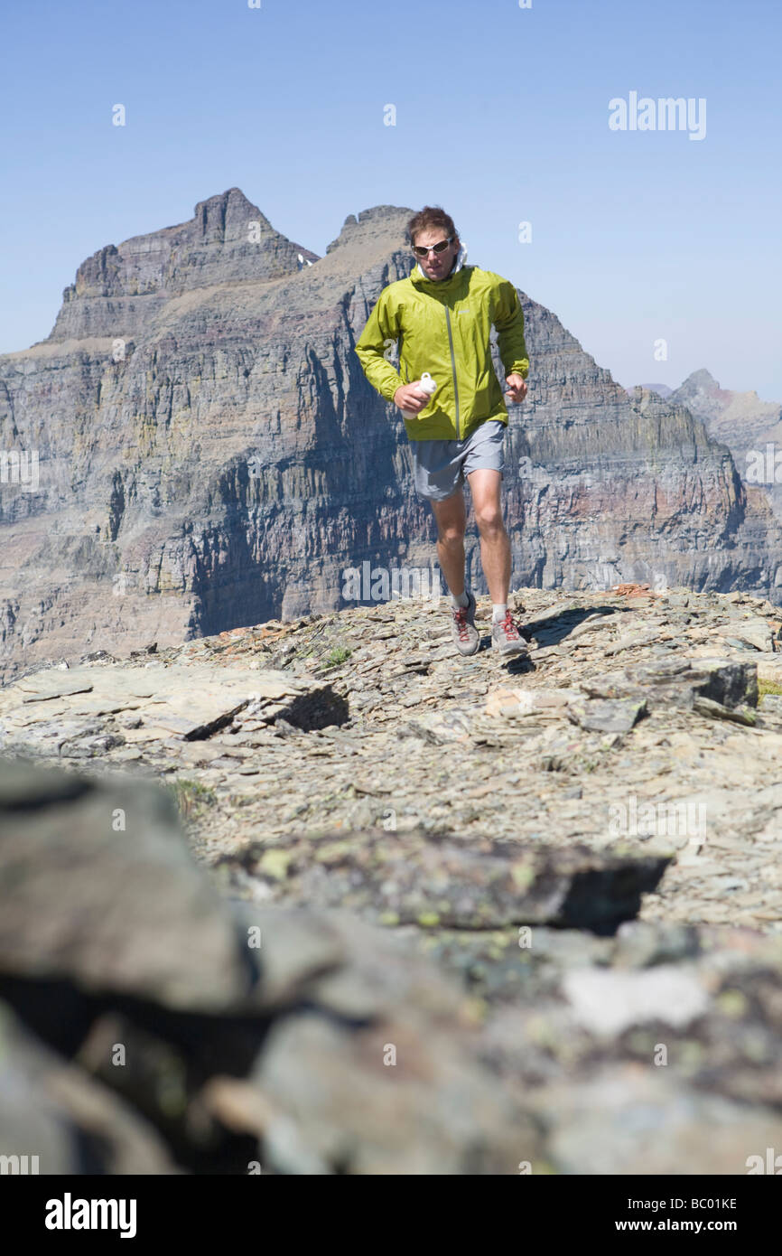 A trail runner makes his way across a rocky path in Glacier National ...