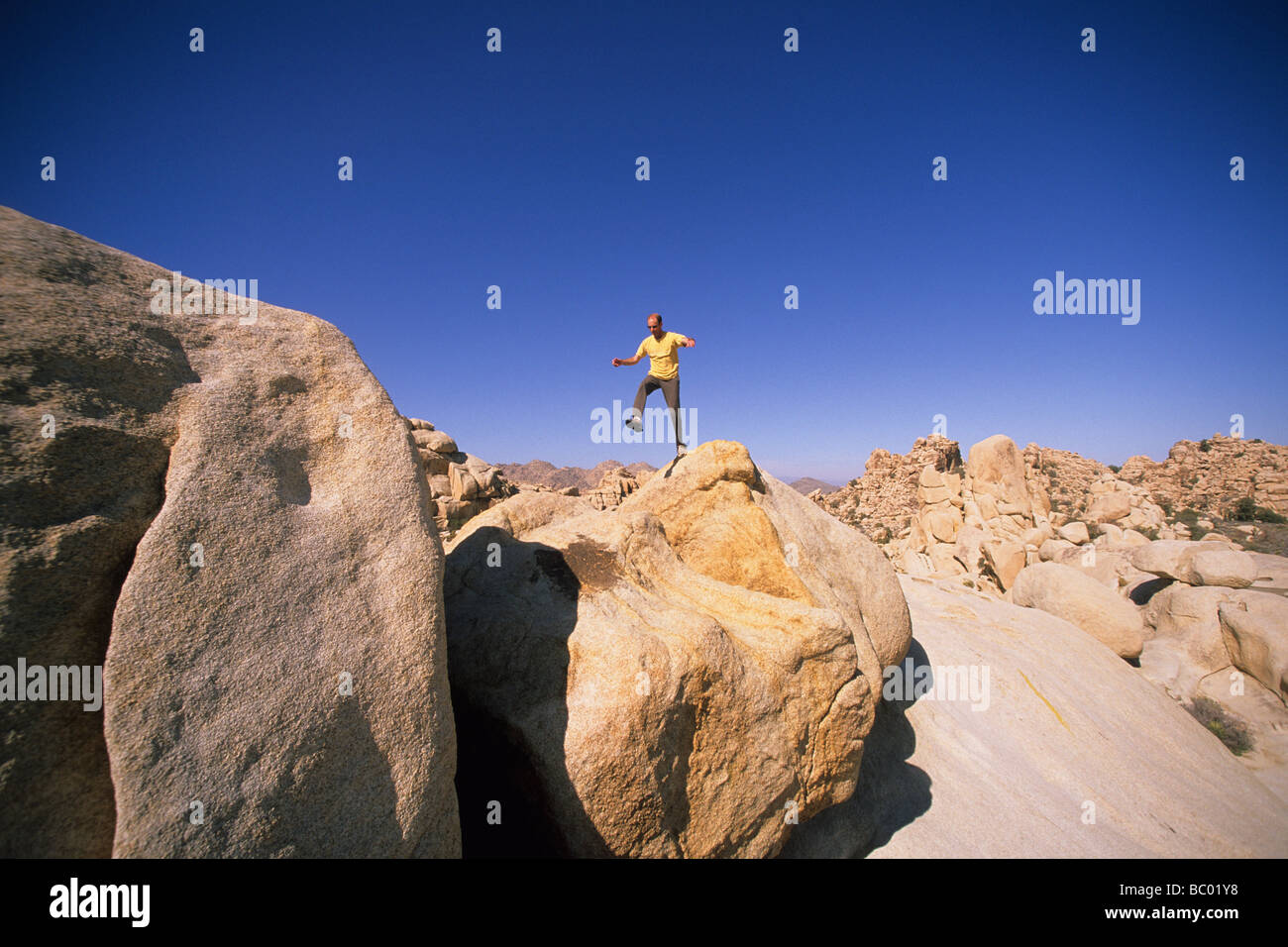 Male hiker leaps from a boulder Stock Photo - Alamy