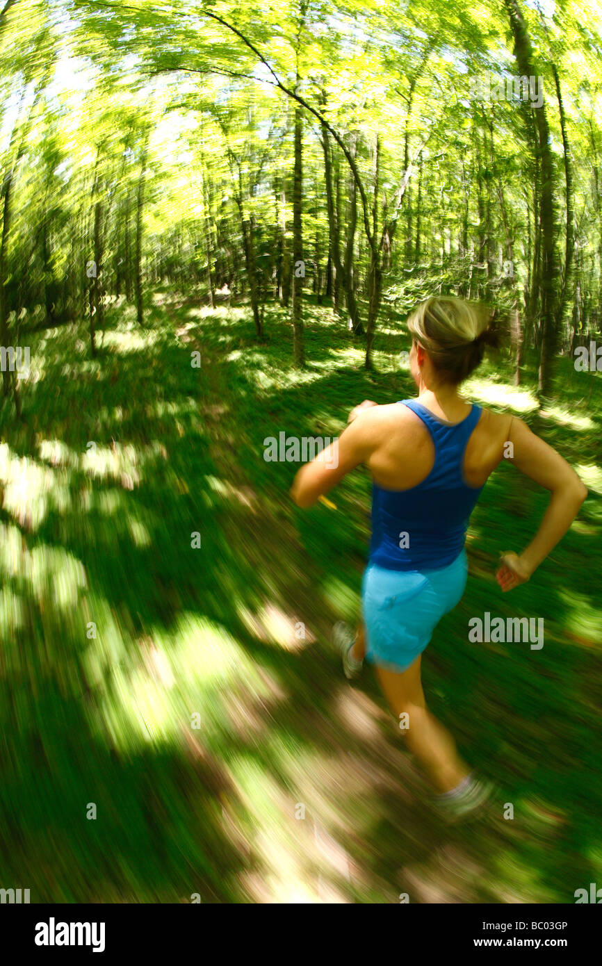 Motion blur image of young woman running through a lush forest Stock ...