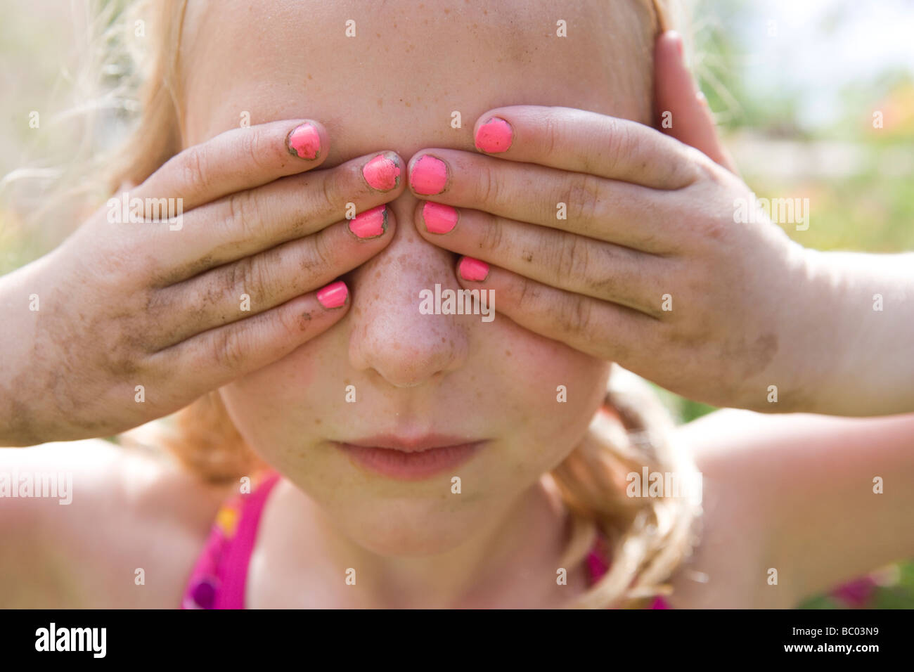 girl holding hands up to her face, covering her eyes, with pink ...
