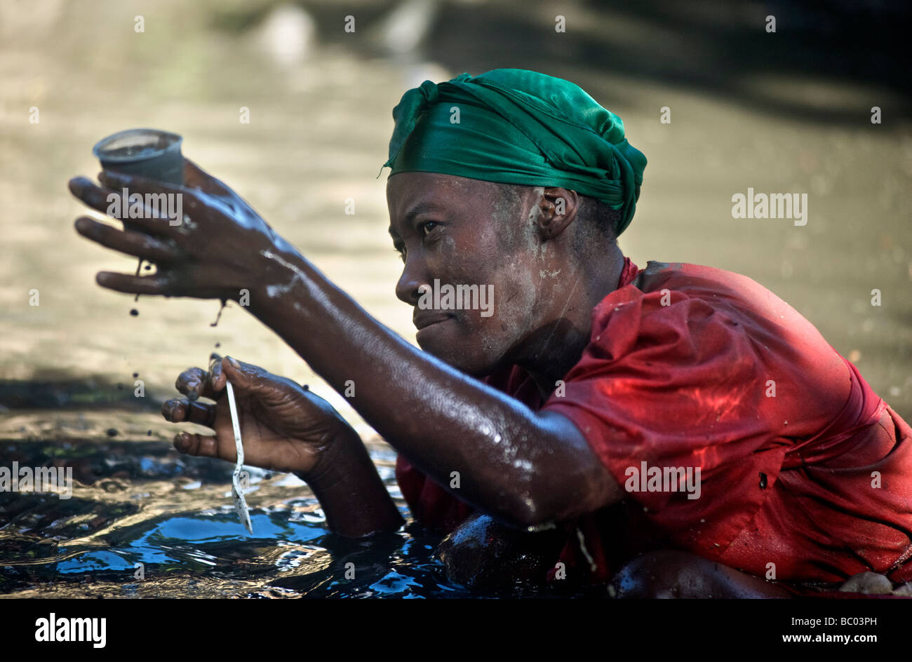 A voodoo priestess mixes up a potion during a voodoo ceremony in a mud ...