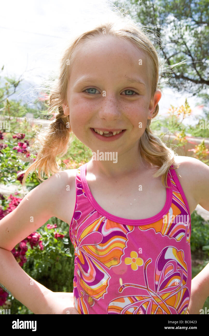 portrait of confident seven year old girl smiling outdoors, summer ...