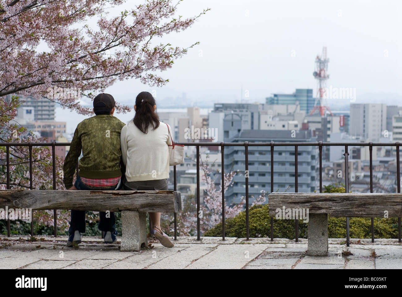 Couple in love sits on a park bench overlooking the city of Otsu in ...